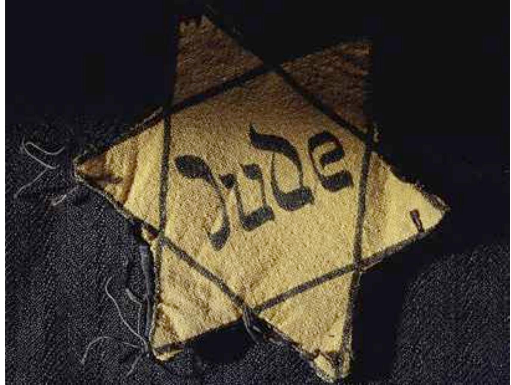 Yellow star of david badge with hebraic lettering of “jude”.