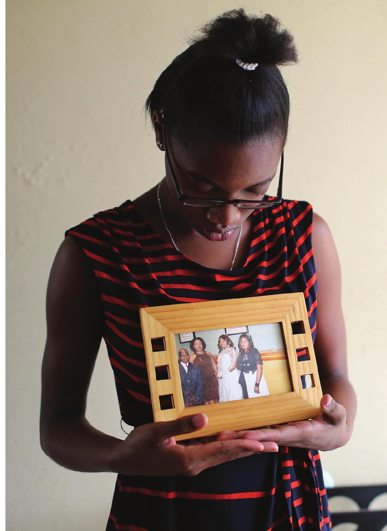 Sandy, age 13, holds a picture of her mother, sonia, who was