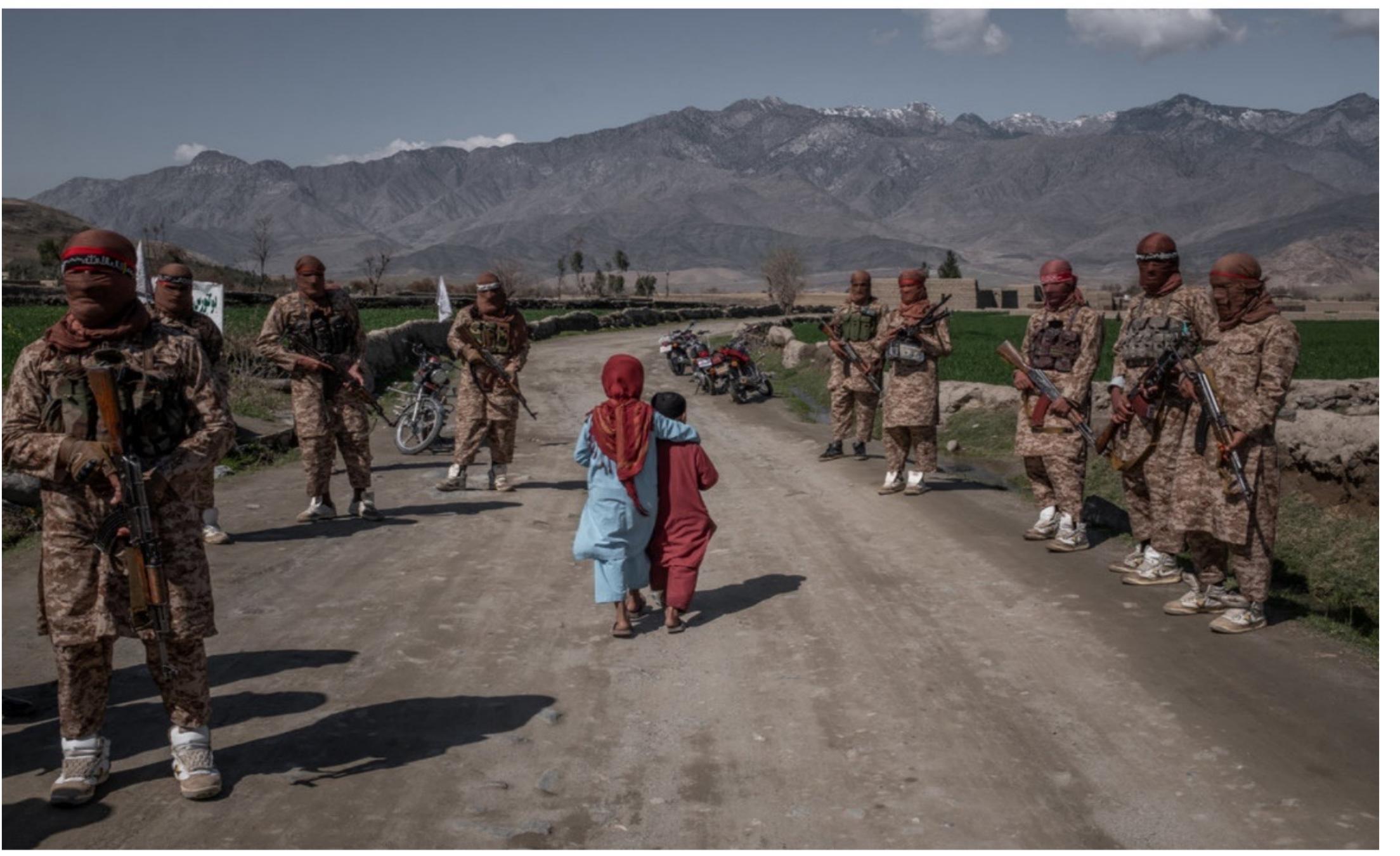 Two boys pass members of a taliban red unit, an elite force,