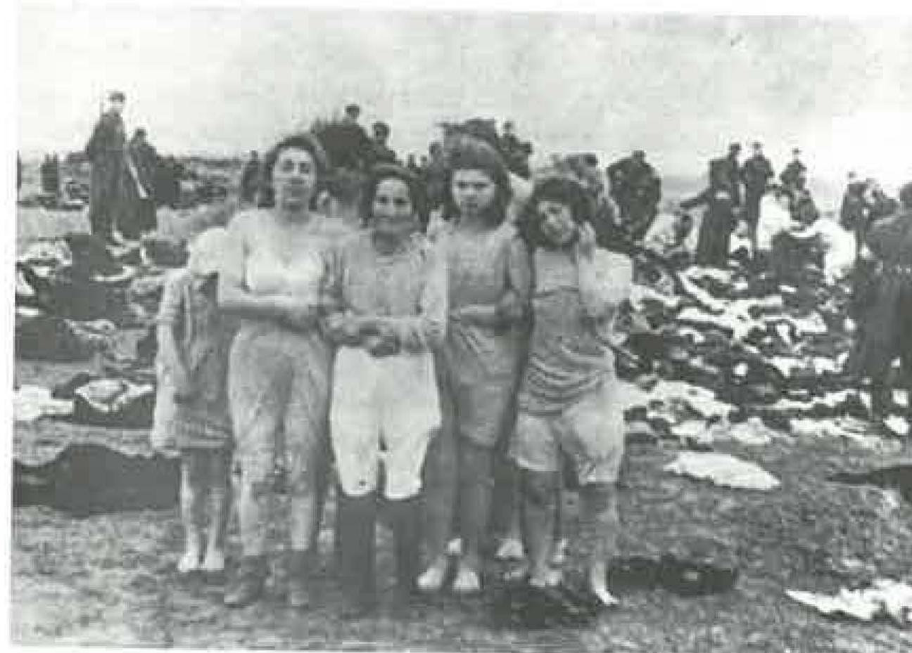 A group of jewish women and girls huddle together on a beach